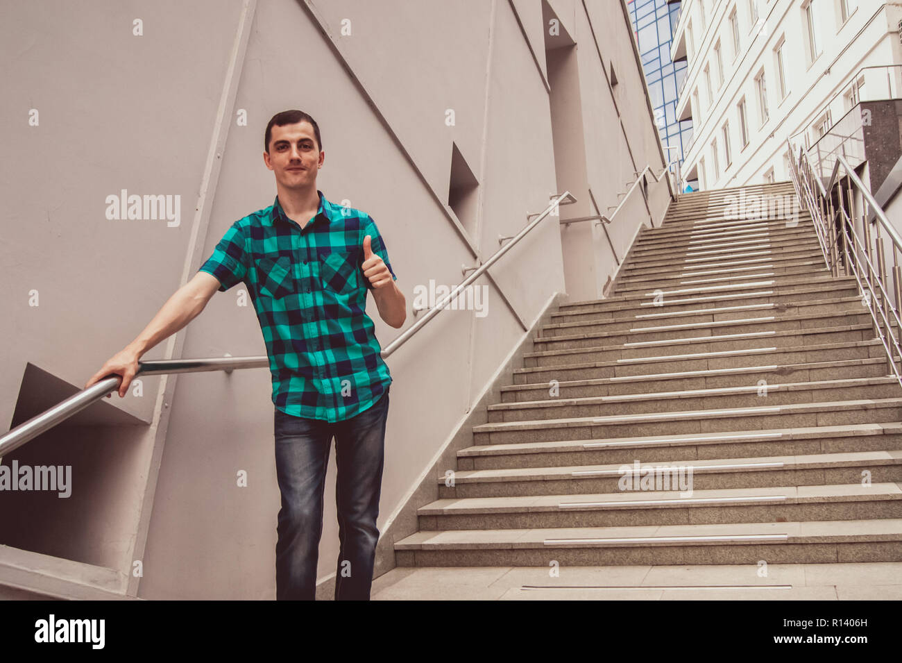 A young man stands on a big ladder and raises his thumb up Stock Photo ...
