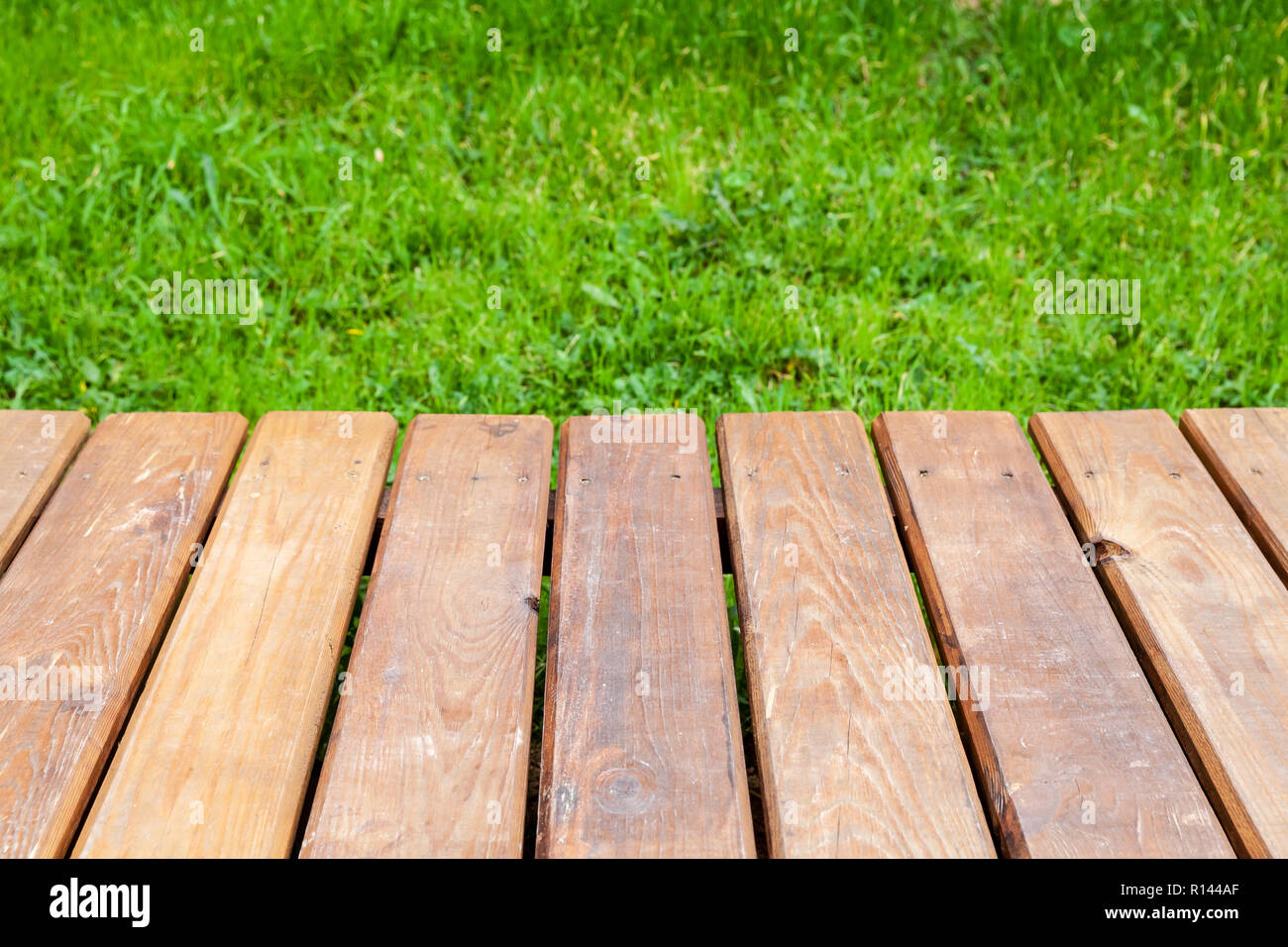 Perspective view of wooden boardwalk over lawn with green grass, park ...