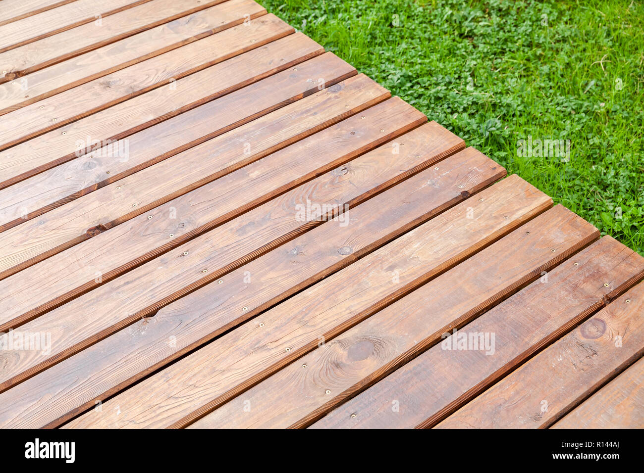 New shiny wooden boardwalk over lawn with green grass, modern park ...