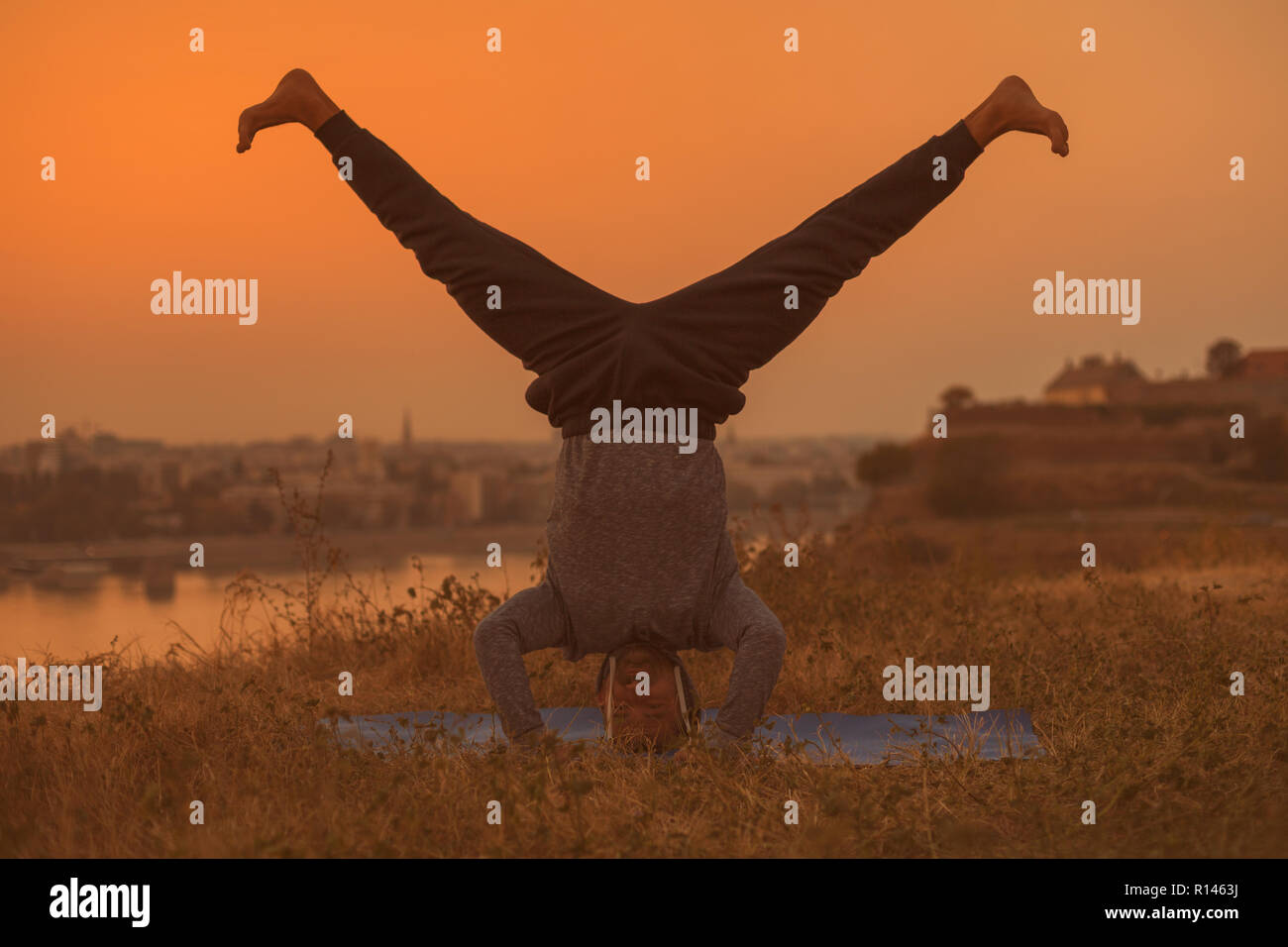 Man doing yoga on sunset with city view,Headstand /Shirshasana Stock ...