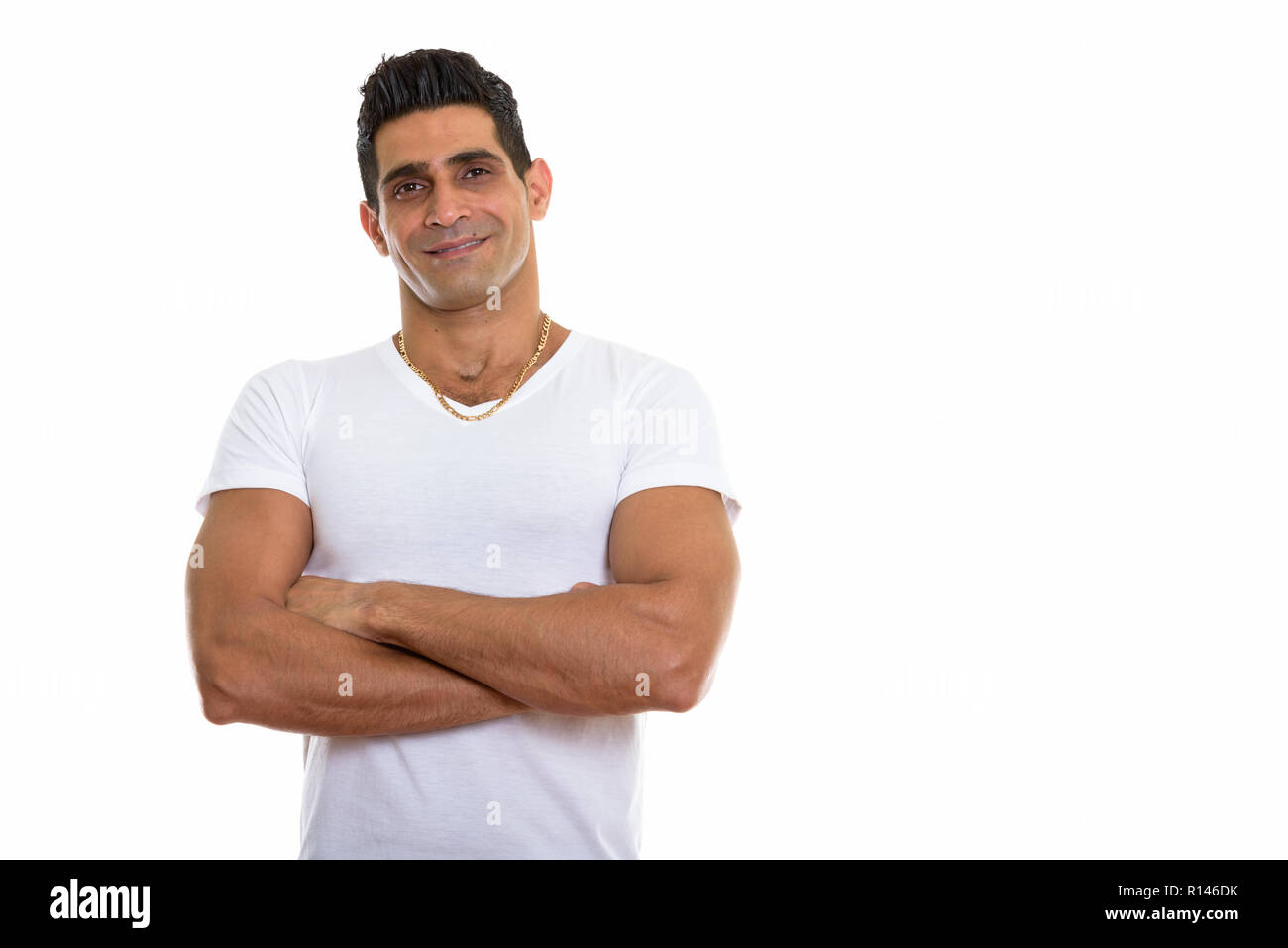 Studio shot of young happy Persian man smiling with arms crossed Stock ...