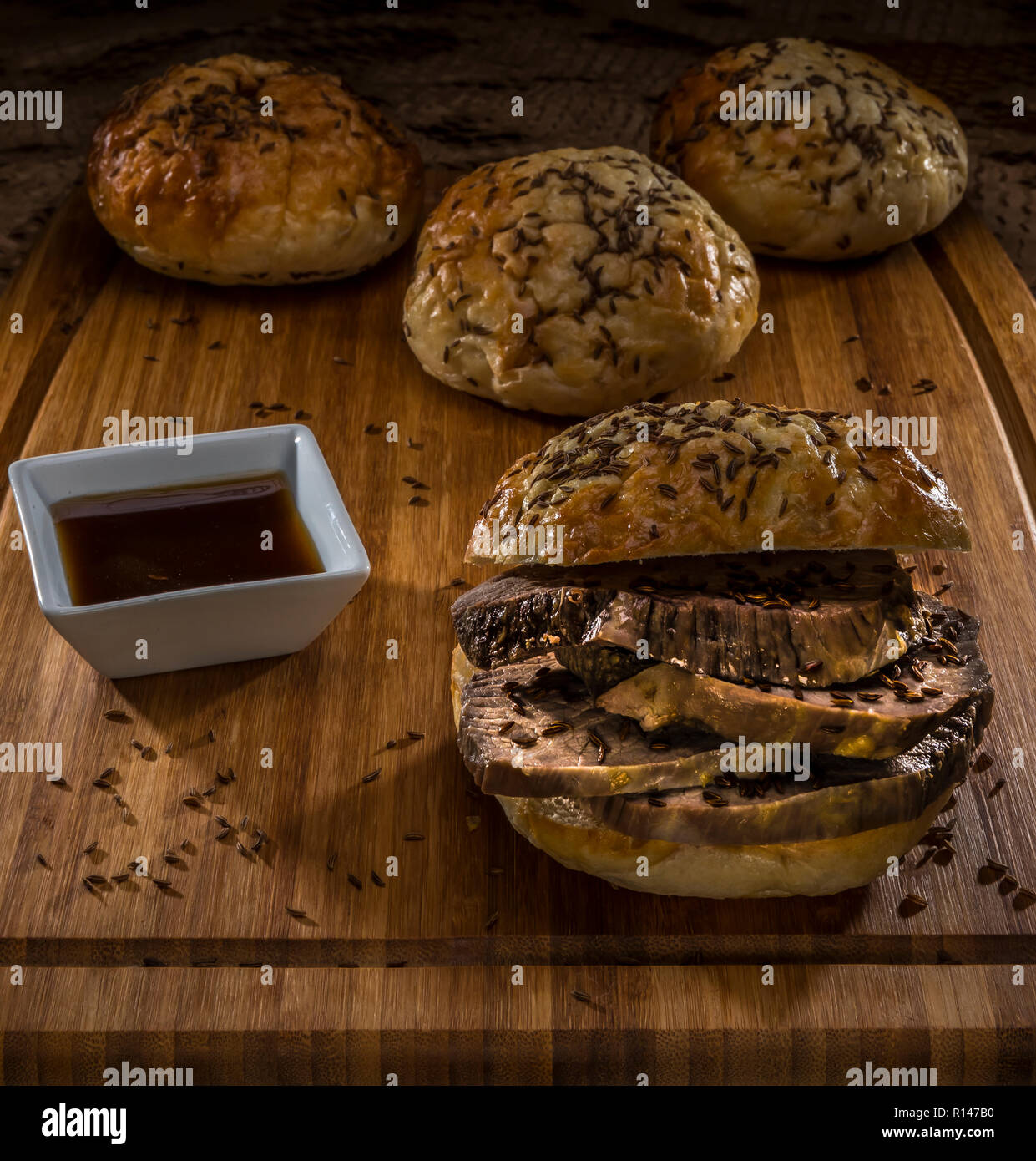 roastbeef on kimmelweck roll on wooden cutting board with au jus Stock ...