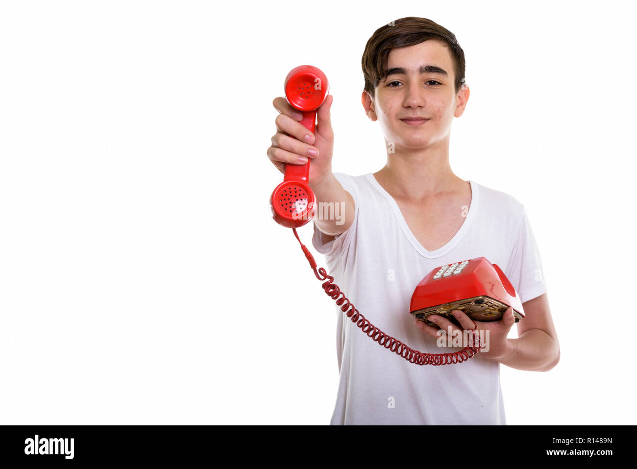 Studio shot of young handsome Persian teenage boy giving old tel Stock ...