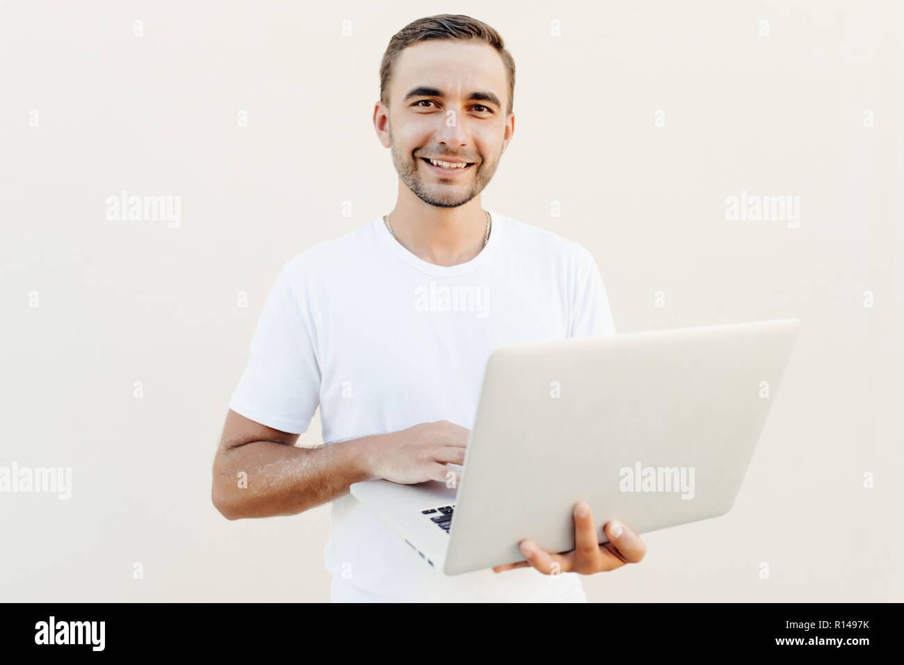 Portrait of smiling male student using a laptop on white background ...