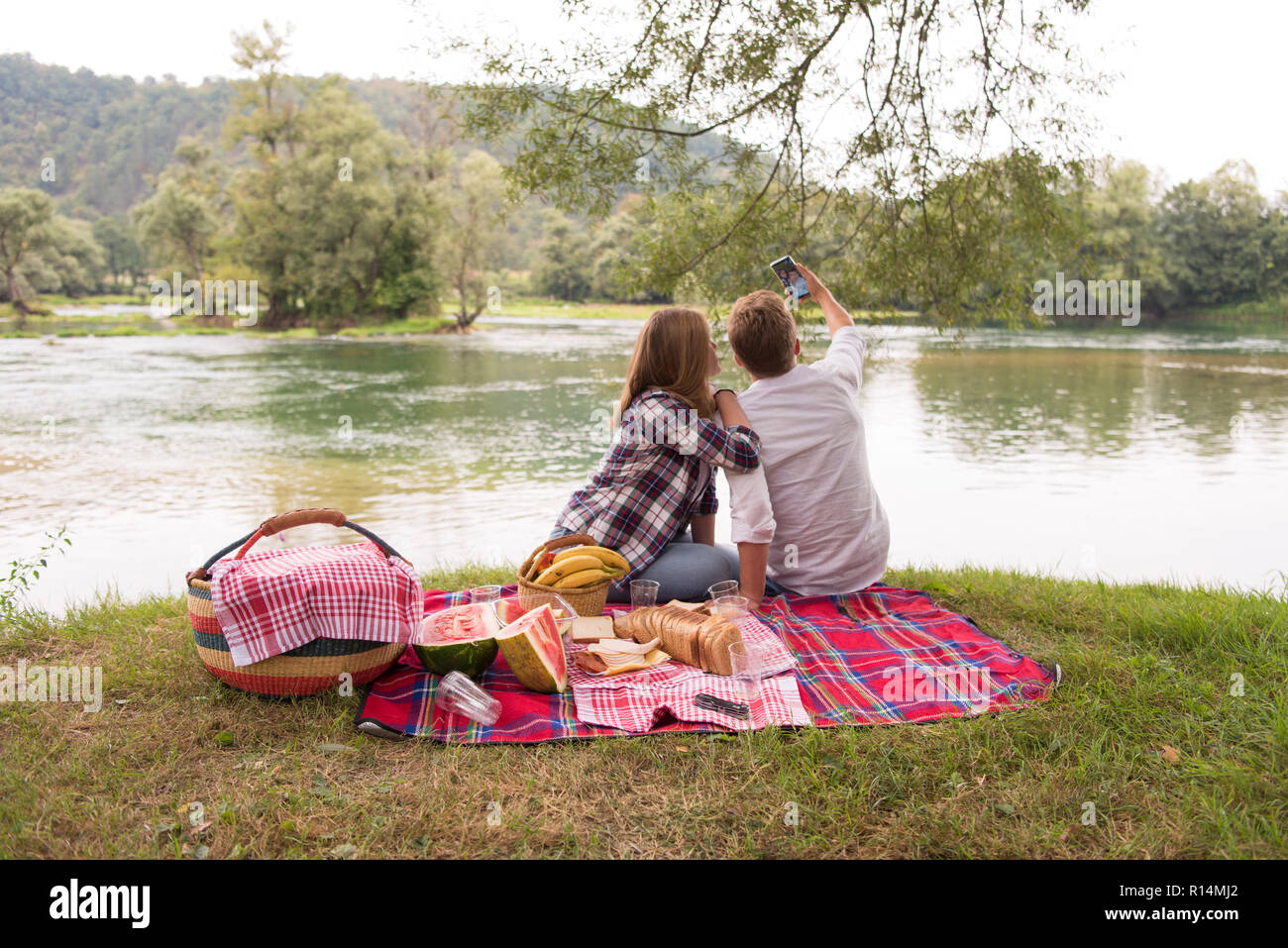 Couple in love taking a selfie by mobile phone while enjoying picnic ...