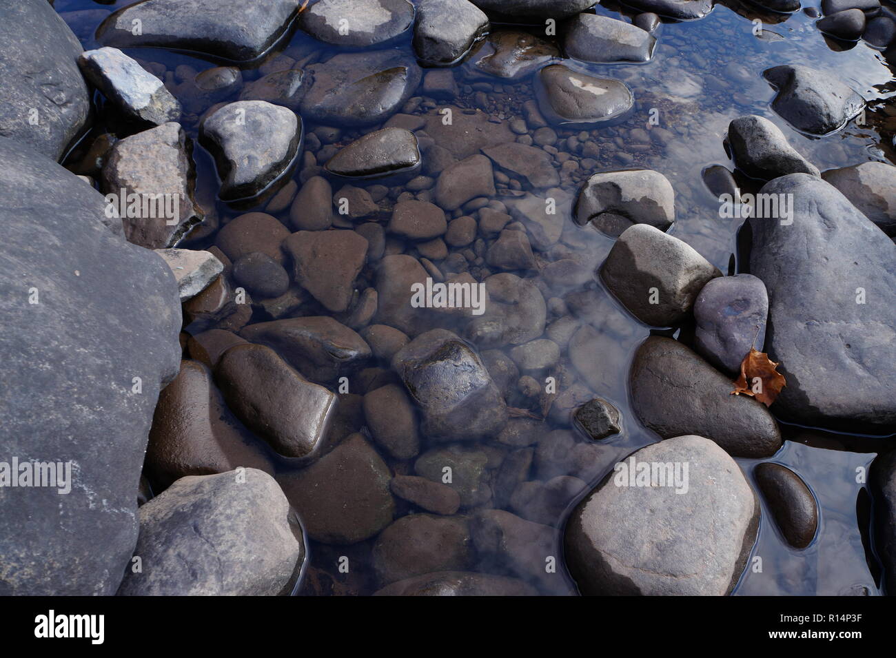 a still stream of shallow water with many rocks in it Stock Photo - Alamy