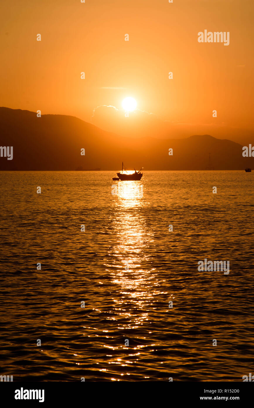 Fishing boat in the rays of the rising sun Stock Photo - Alamy