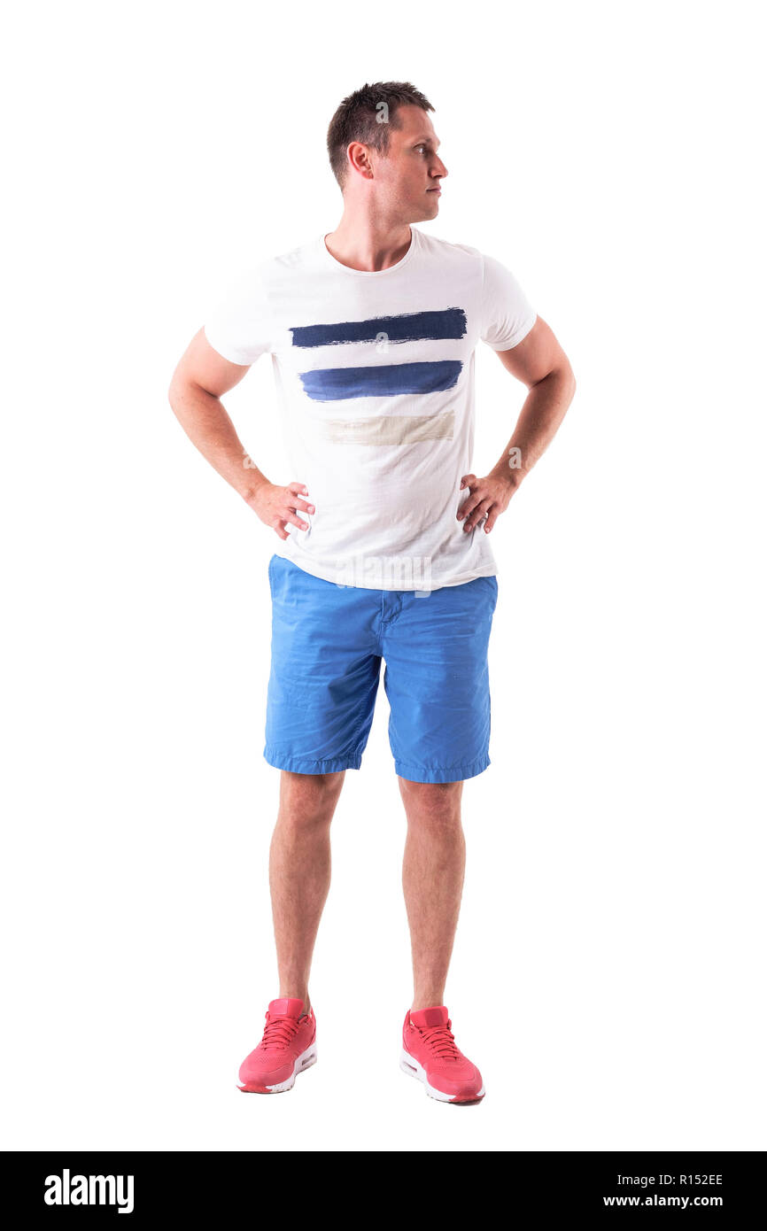 Serious young sporty man with arms on hips looking away over the ...