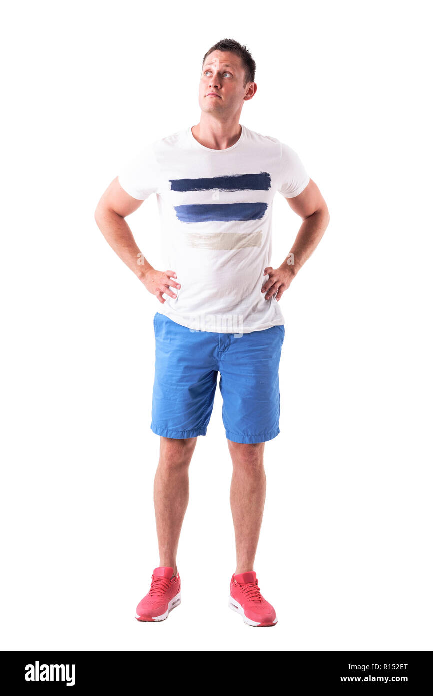 Confused casual man in sporty clothes looking up with arms on hips ...