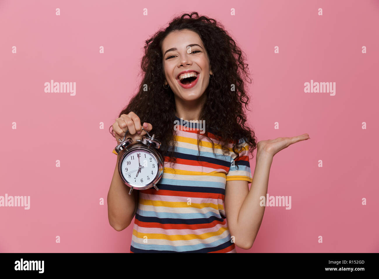 Photo of caucasian woman 20s with curly hair holding alarm clock ...