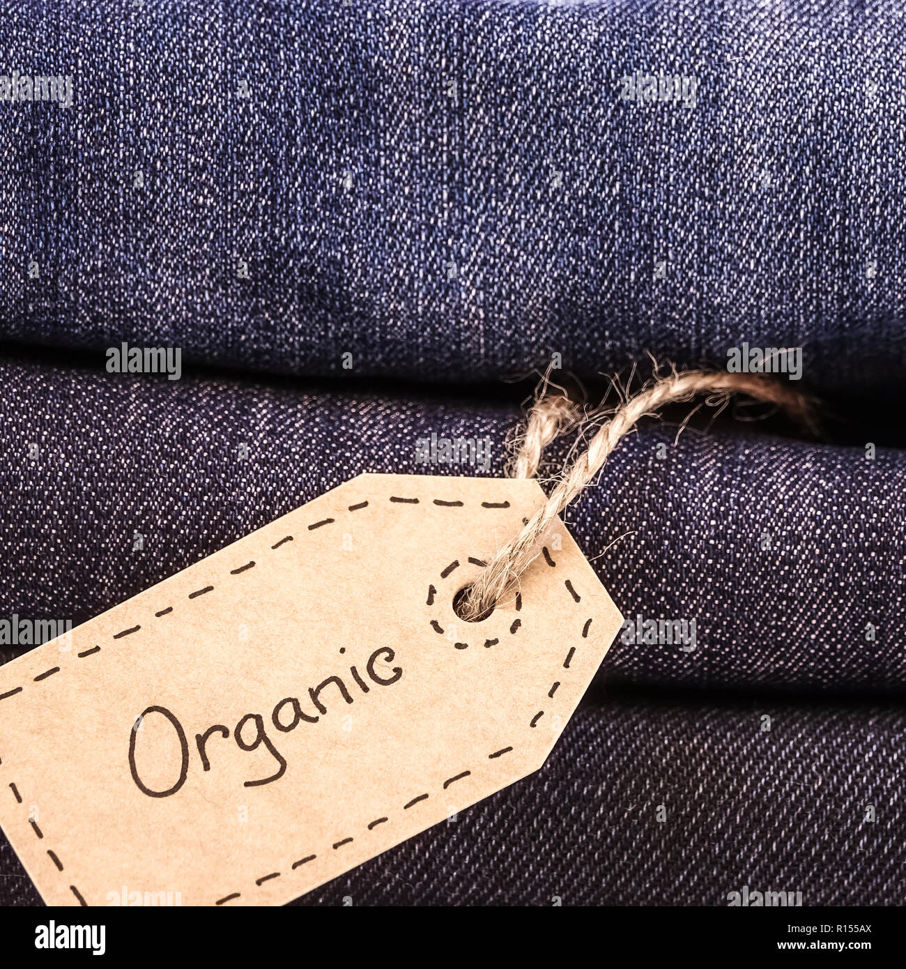 Organic blue jeans. Denim pants pile. Eco clothes tag Stock Photo - Alamy