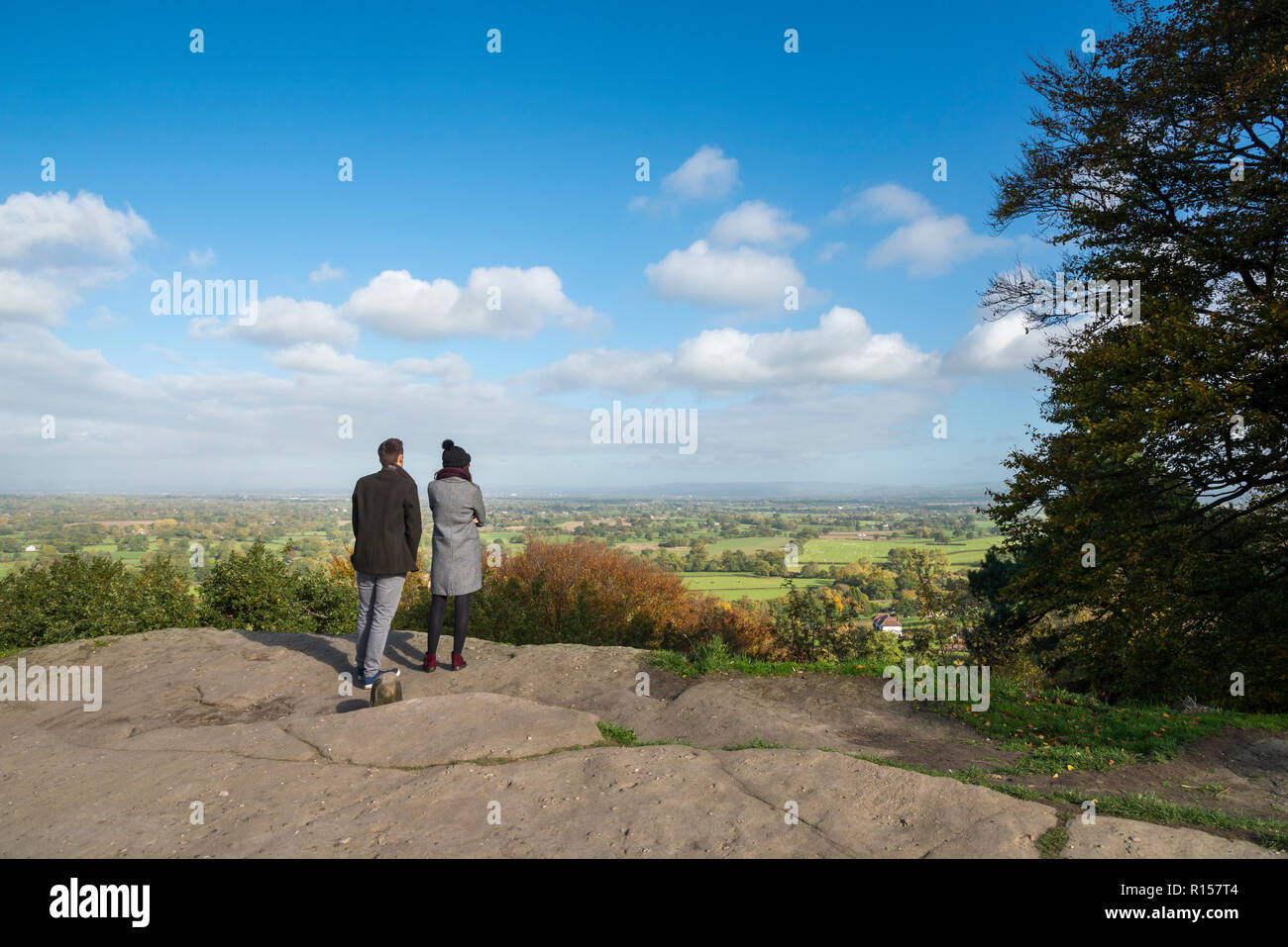 Young couple stood looking at the Cheshire countryside from Alderley ...