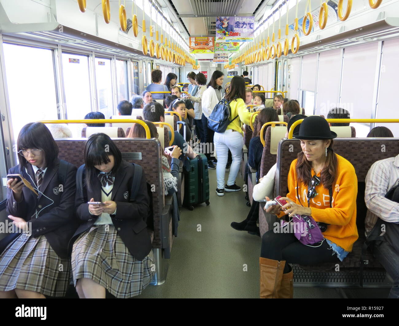 Commuters standing on a busy Japanese train; most of them texting on ...