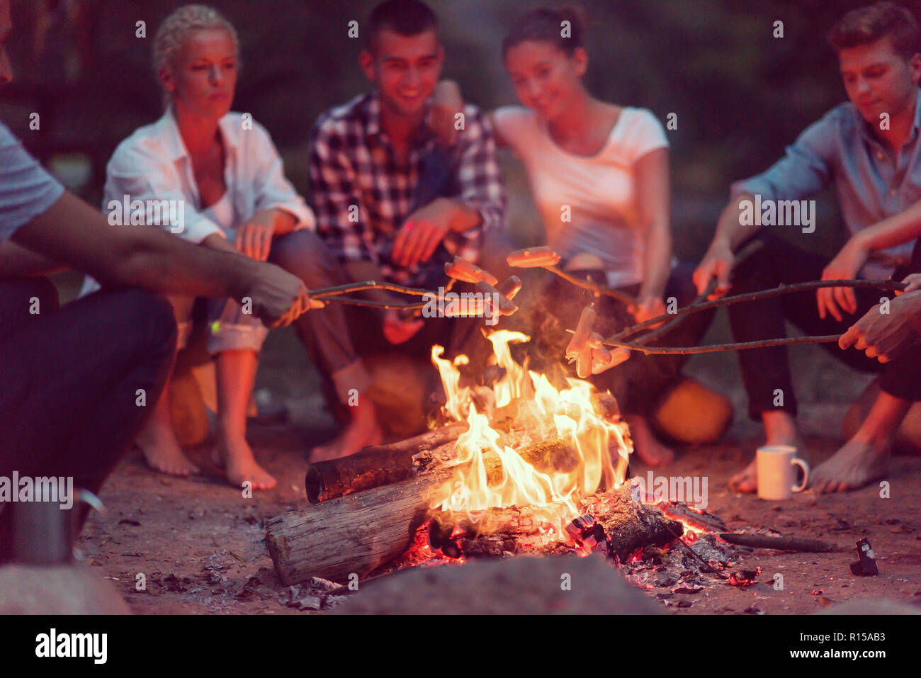a group of happy young friends relaxing and enjoying summer evening ...
