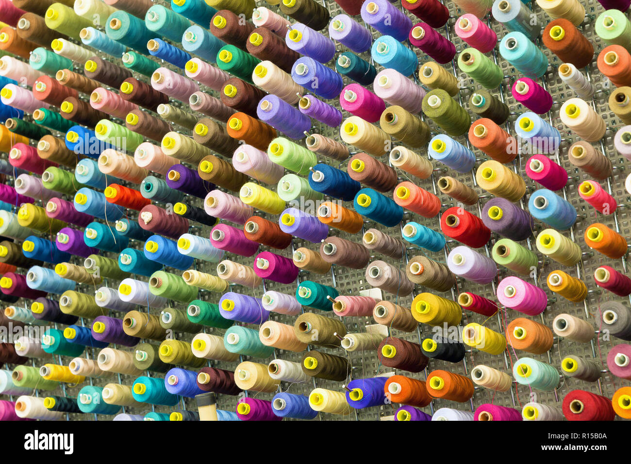 Organized wall of spools with sewing threads in many color variations ...