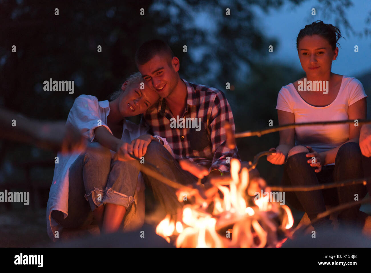 a group of happy young friends relaxing and enjoying summer evening ...