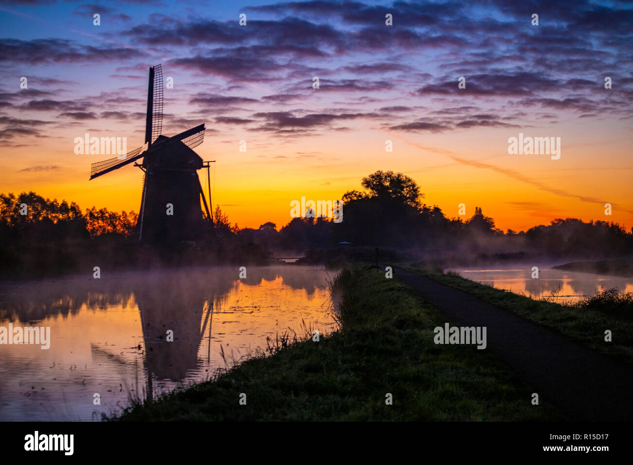 Silhouette of a windmill at the warm and red color sunrise in ...