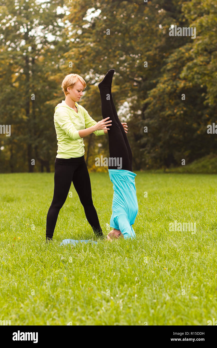 Yoga instructor is showing a woman how to do correct Headstand Stock ...