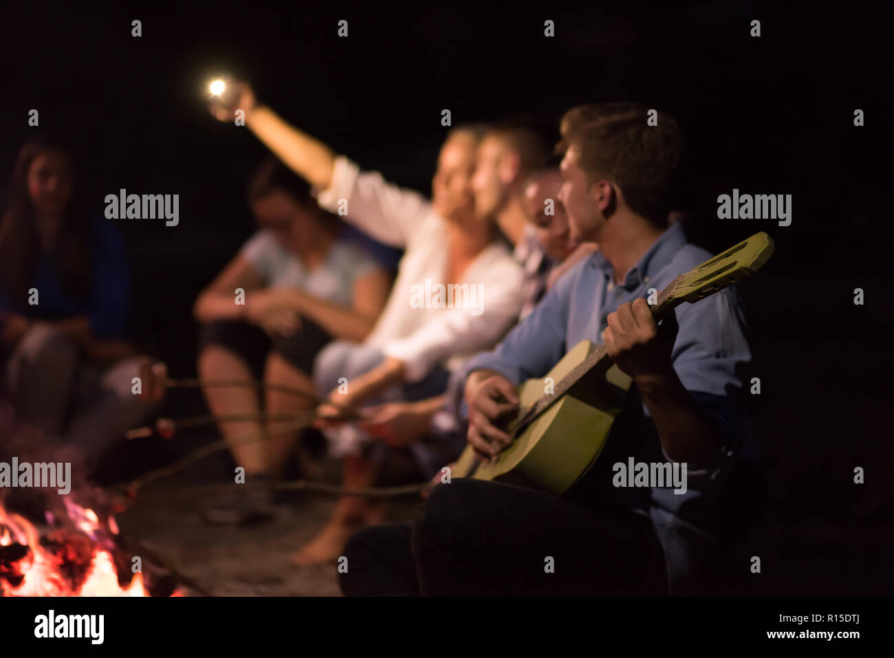 a group of happy young friends relaxing and enjoying summer evening ...