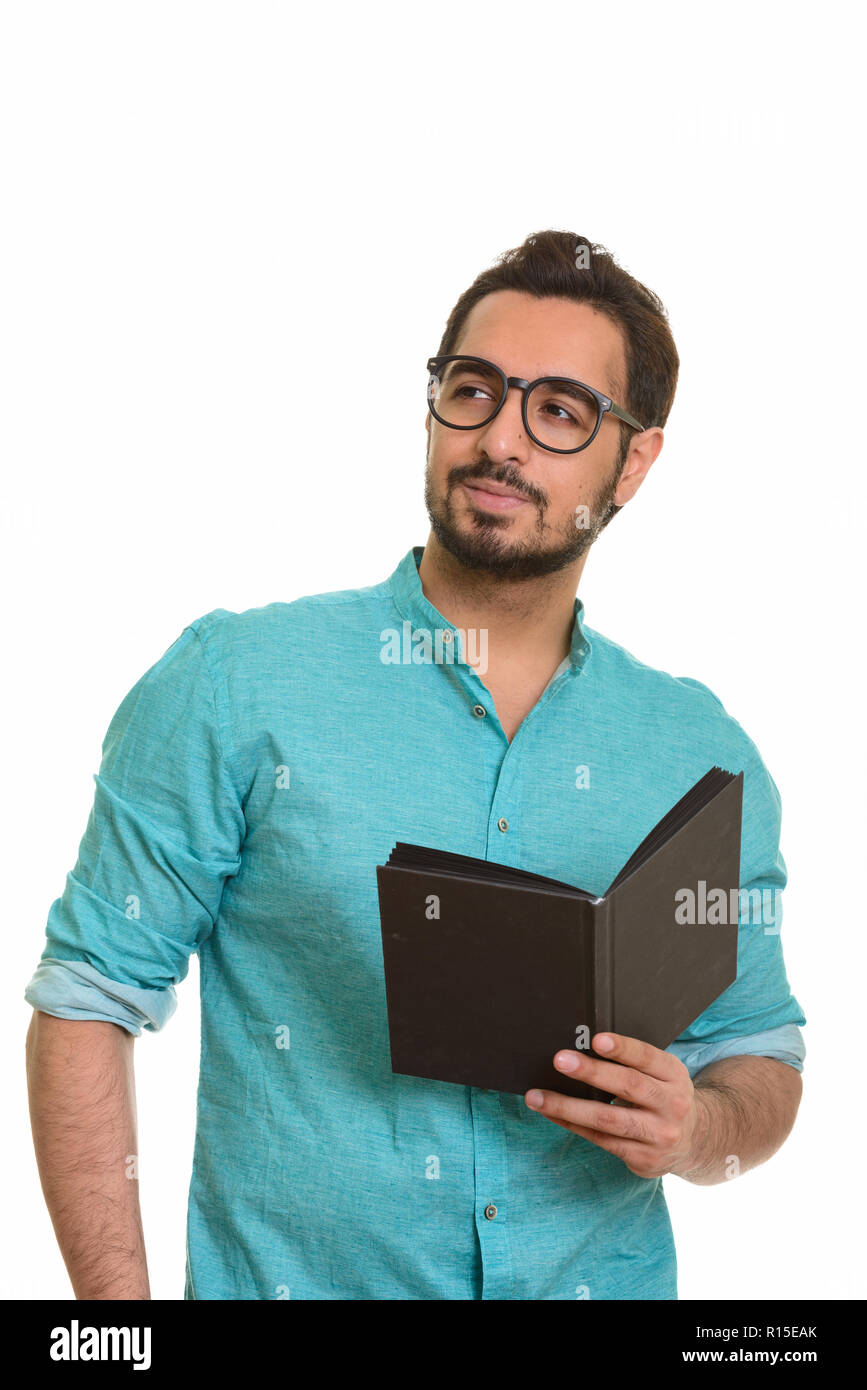 Young handsome Indian man holding book while thinking Stock Photo - Alamy