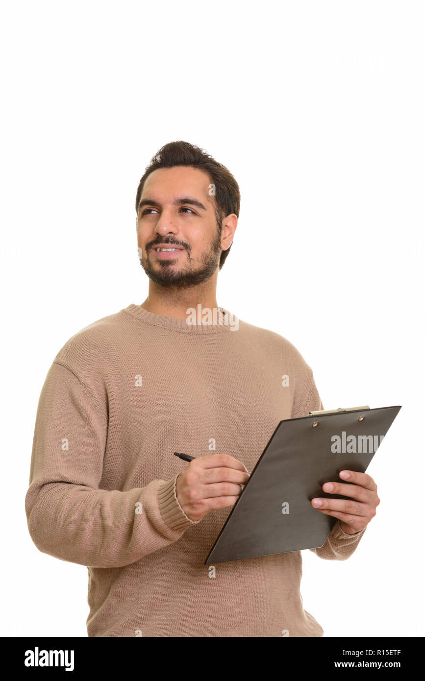 Young happy Indian man writing report on clipboard while thinkin Stock ...