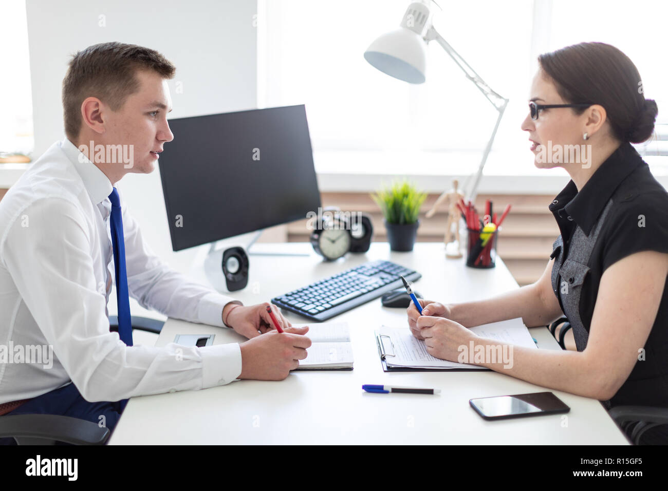 Young people sit in the office at the computer table and work with ...