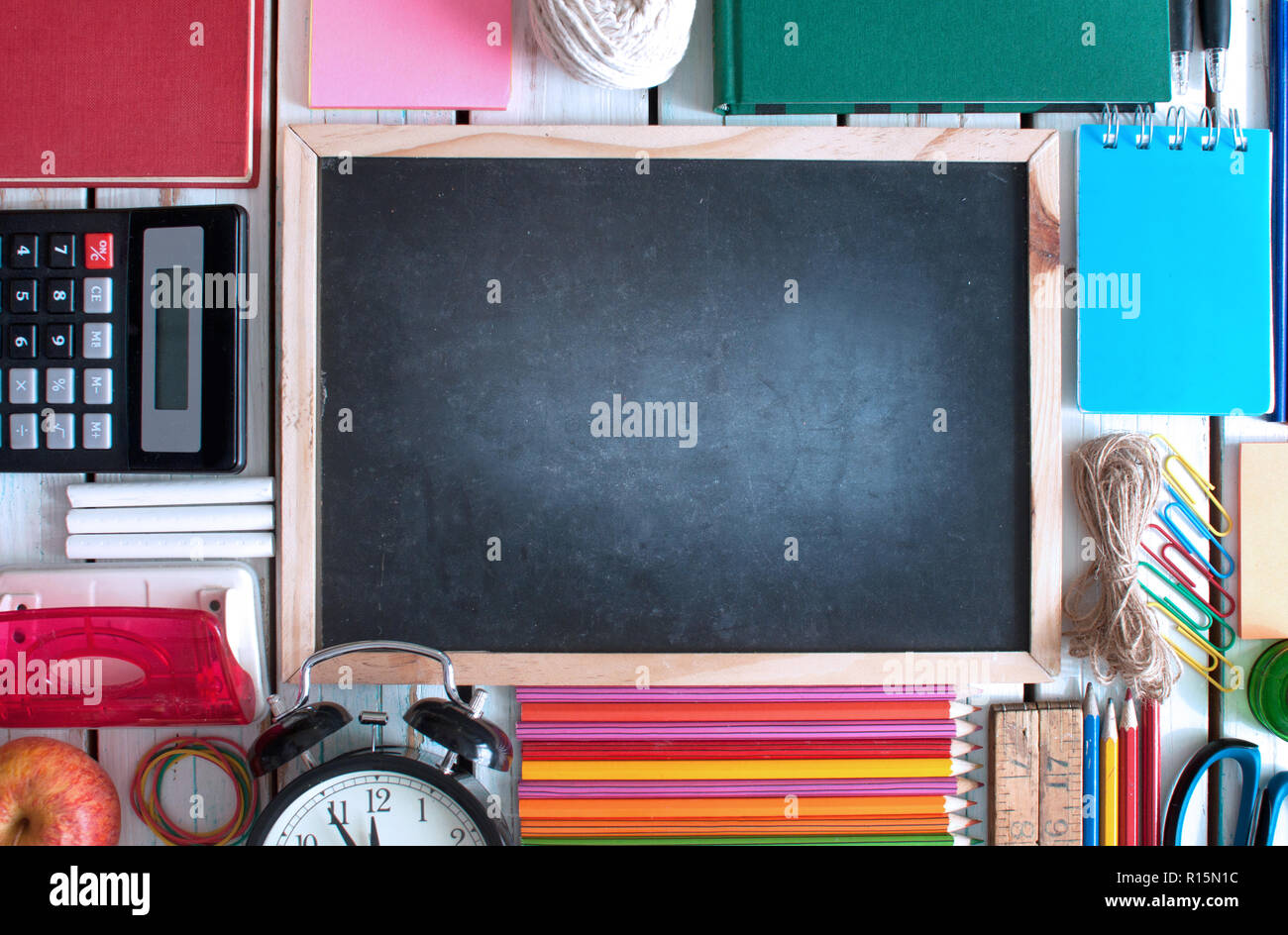 Top view of various stationery objects with blackboard in the centre ...