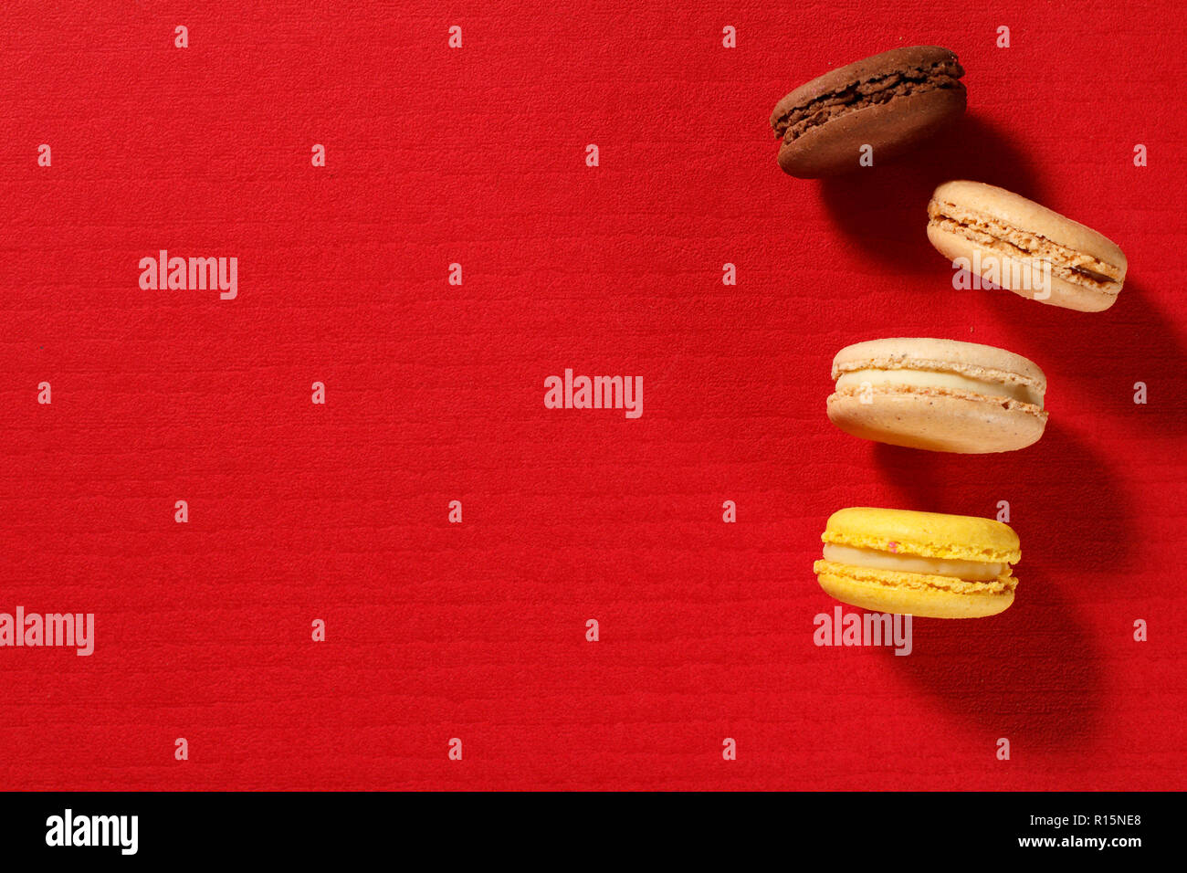 Macarons cakes of different color on red textured surface. Top view ...
