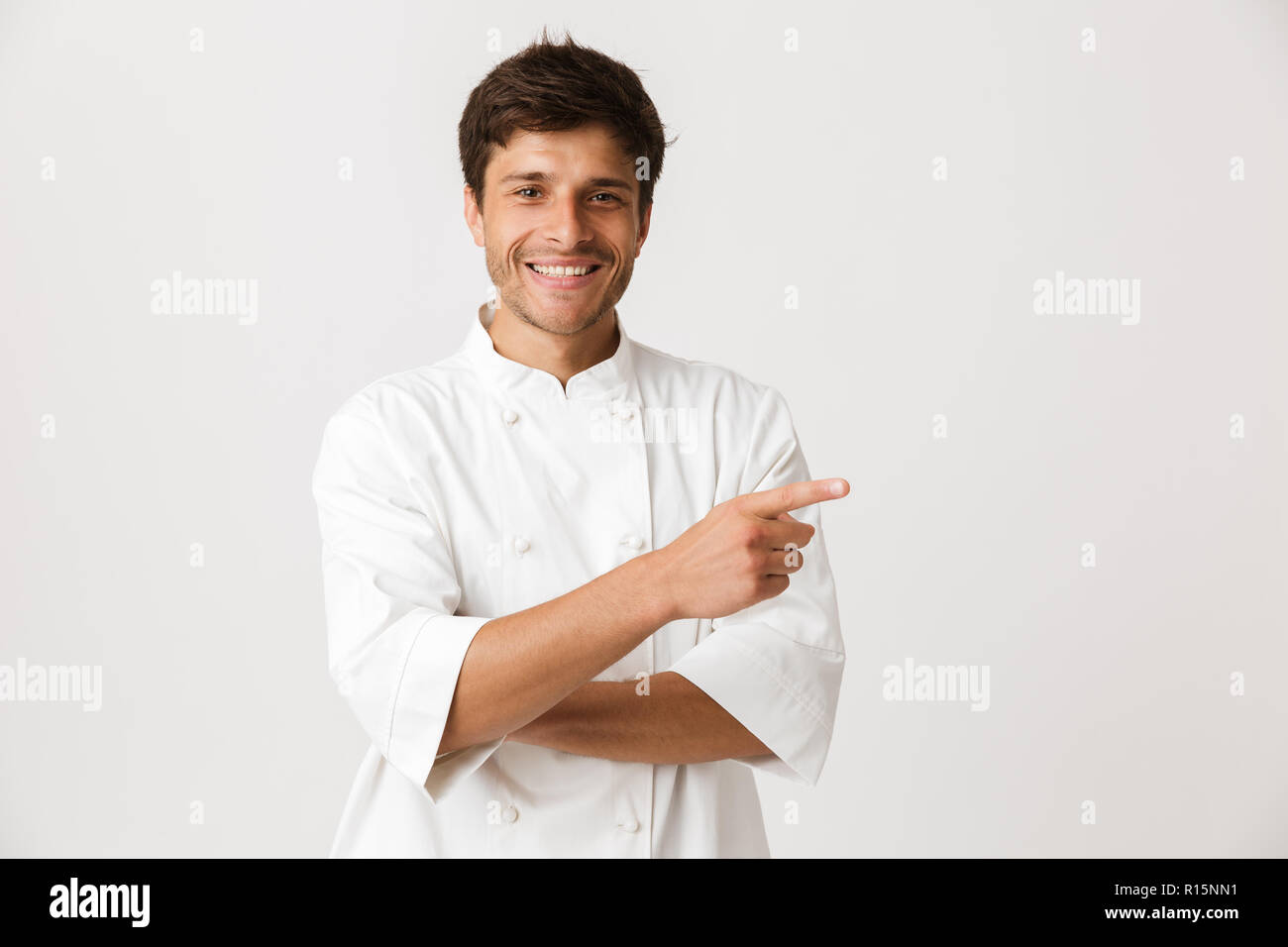 Image of handsome young chef man standing isolated over white wall ...