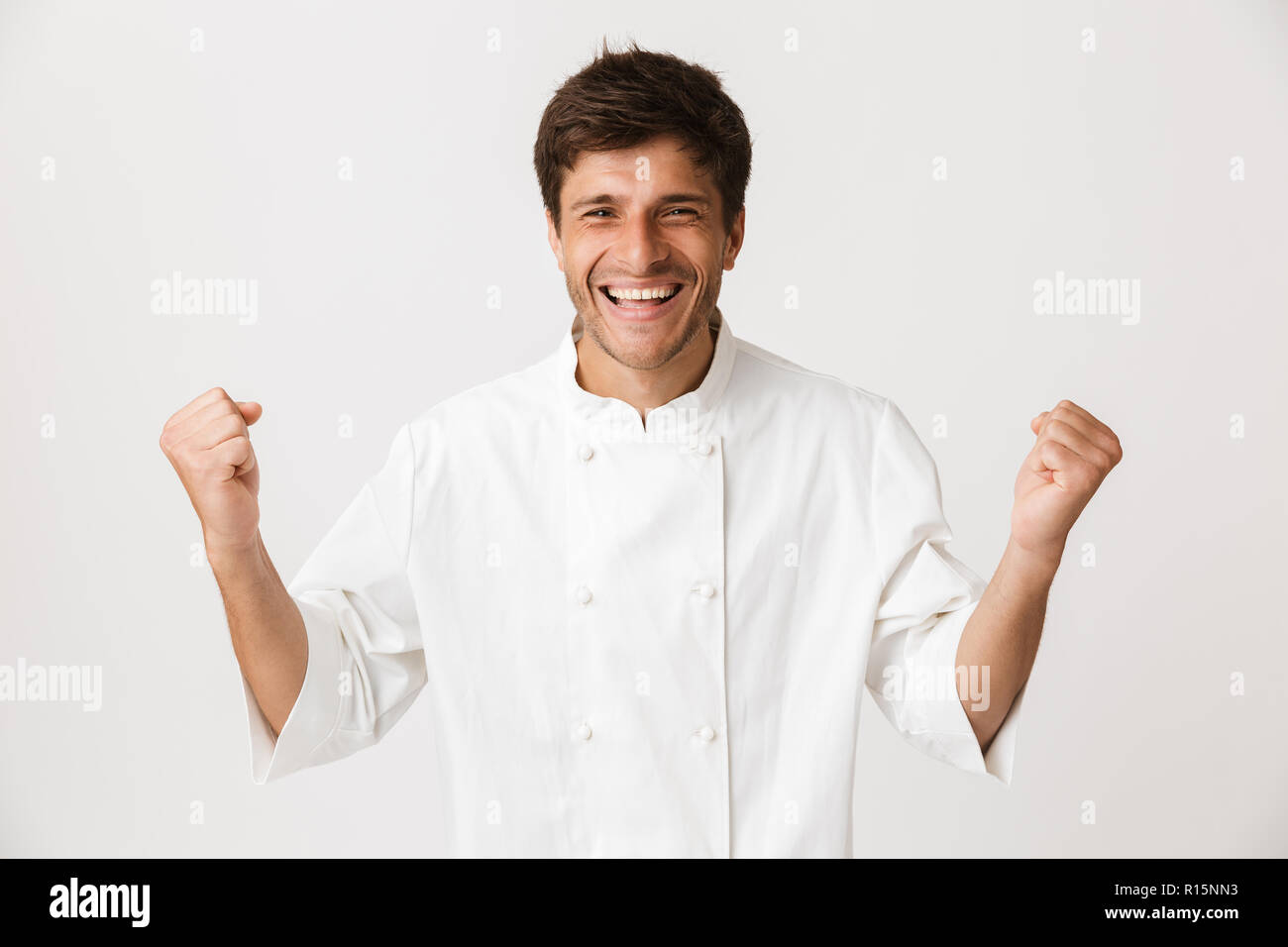 Image of handsome young chef man standing isolated over white wall ...