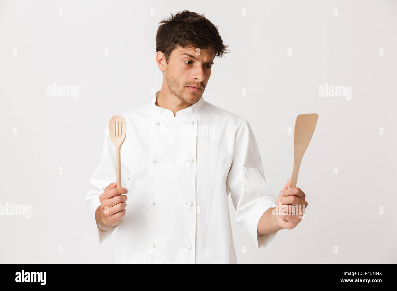 Image of confused young chef isolated over white background holding ...