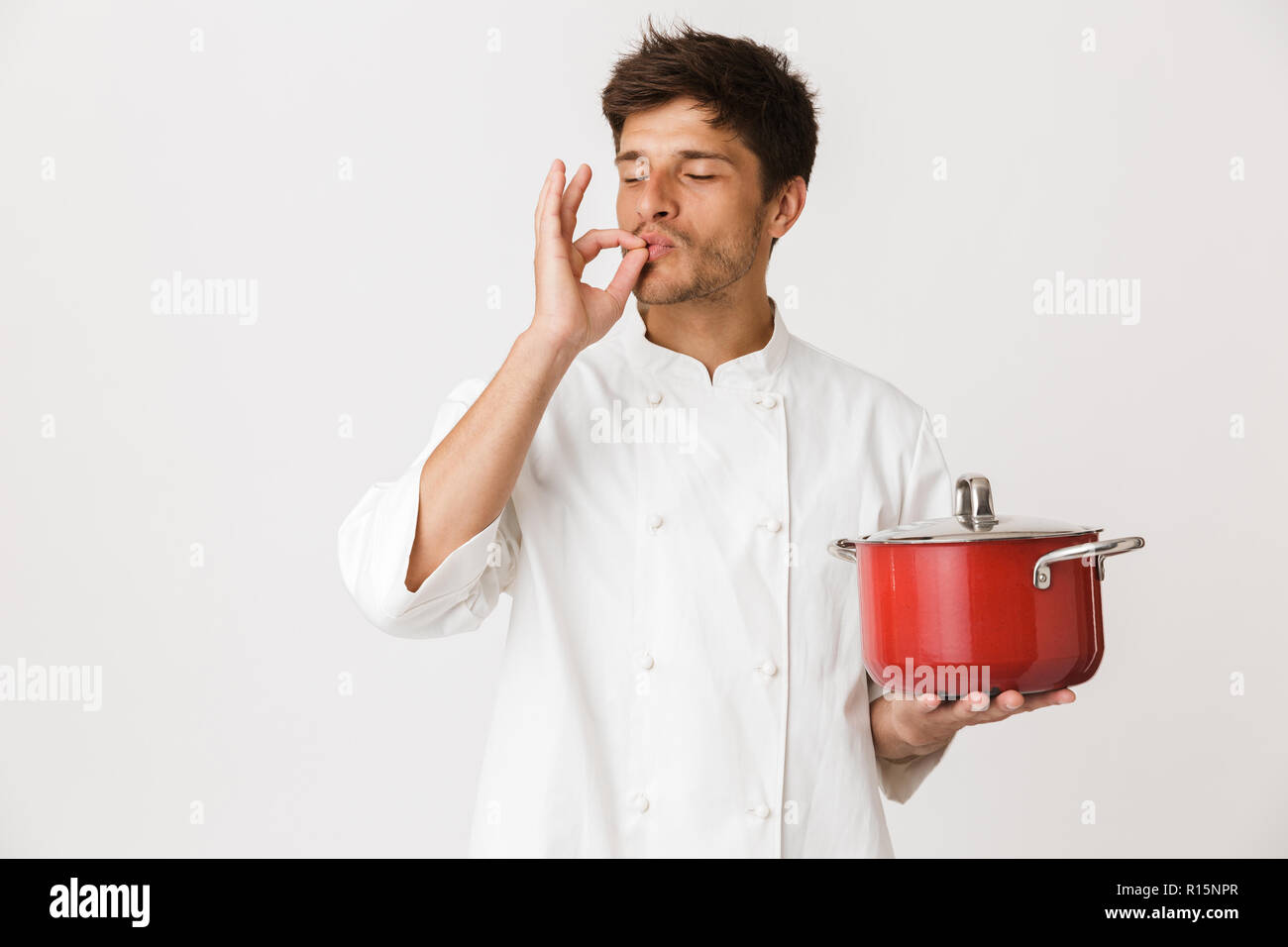 Image of handsome young chef man standing isolated over white wall ...