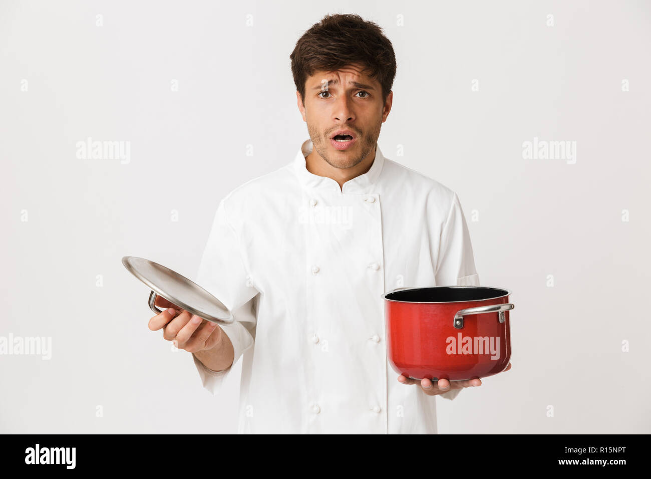 Image of sad confused young chef man standing isolated over white wall ...
