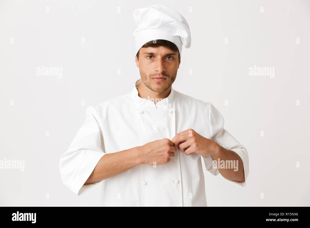 Photo of serious young chef isolated over white background looking ...