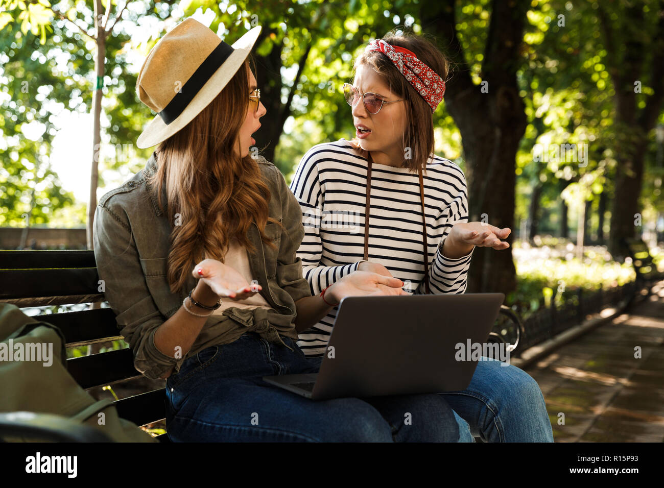 Photo of young confused displeased ladies friends outdoors sitting ...