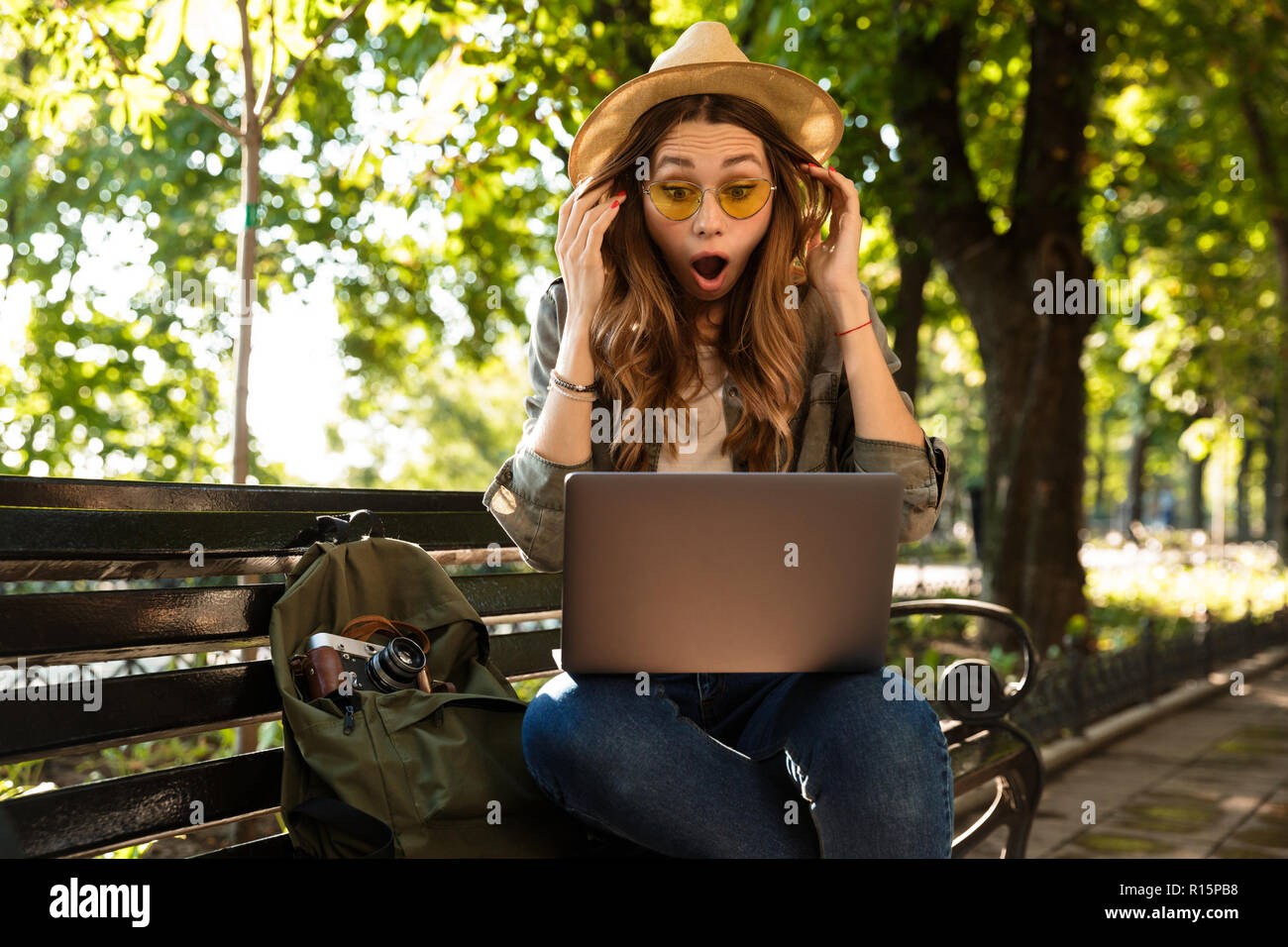 Image of young beautiful excited happy woman outdoors sitting using ...