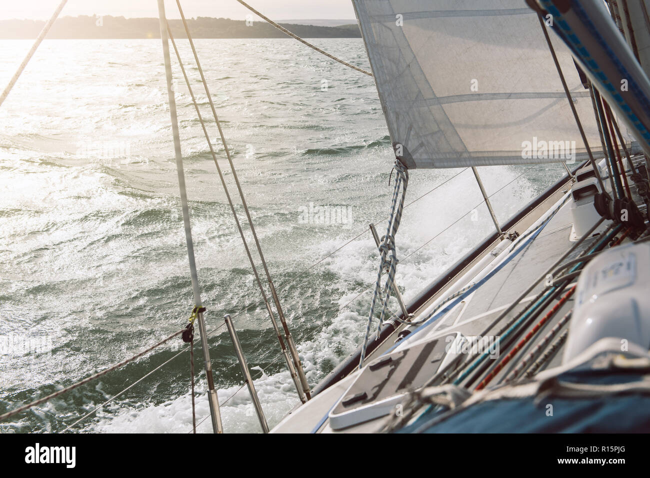 Yacht sailing into low sun Stock Photo - Alamy