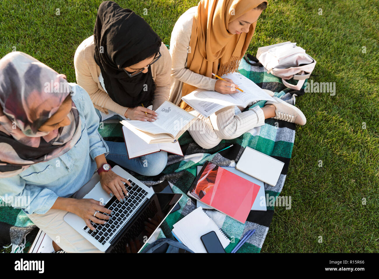 Photo of a happy young arabian women students writing in copybooks in ...
