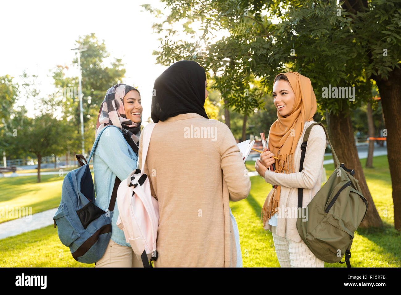 Group of three happy muslim women students carrying backpacks and books ...