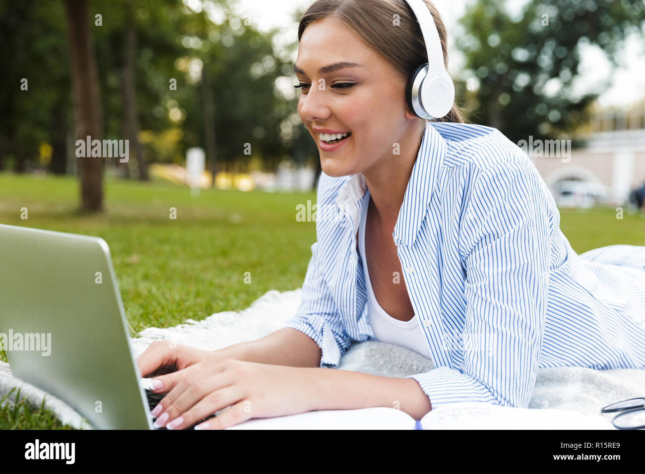 Smiling young girl in headphones spending time at the park, studying ...