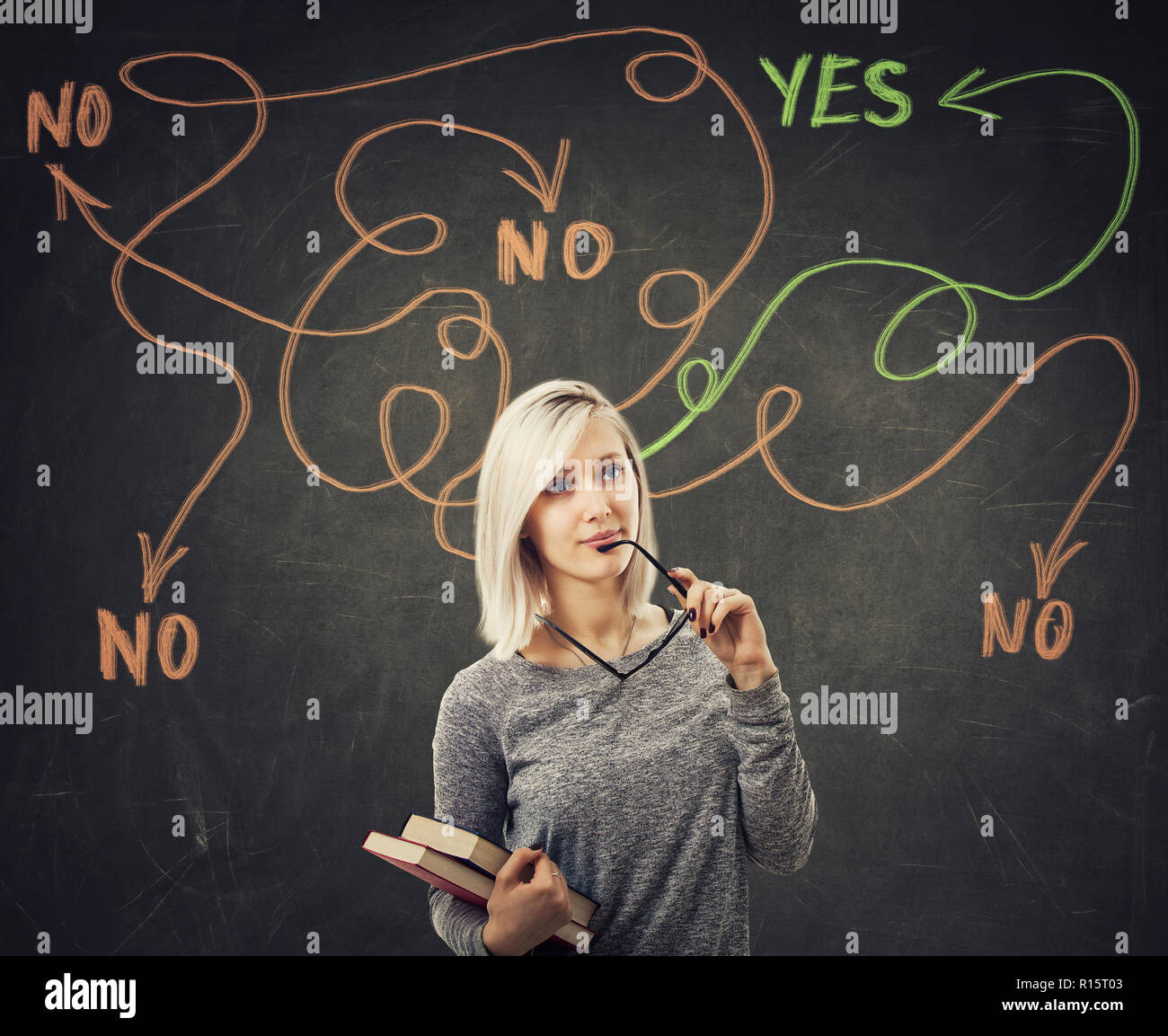 Hard thinking serious smart woman holding books over blackboard ...