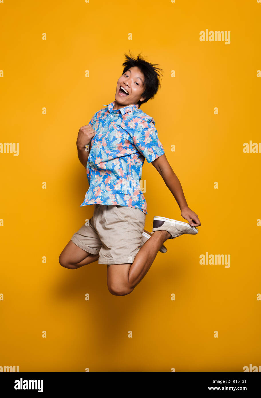 Image of happy emotional young asian man jumping isolated over yellow ...