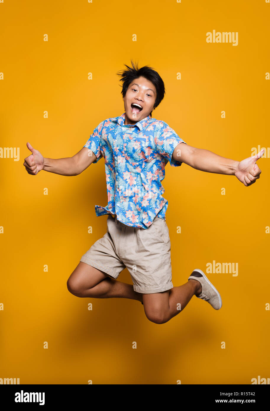 Image of happy emotional young asian man jumping isolated over yellow ...