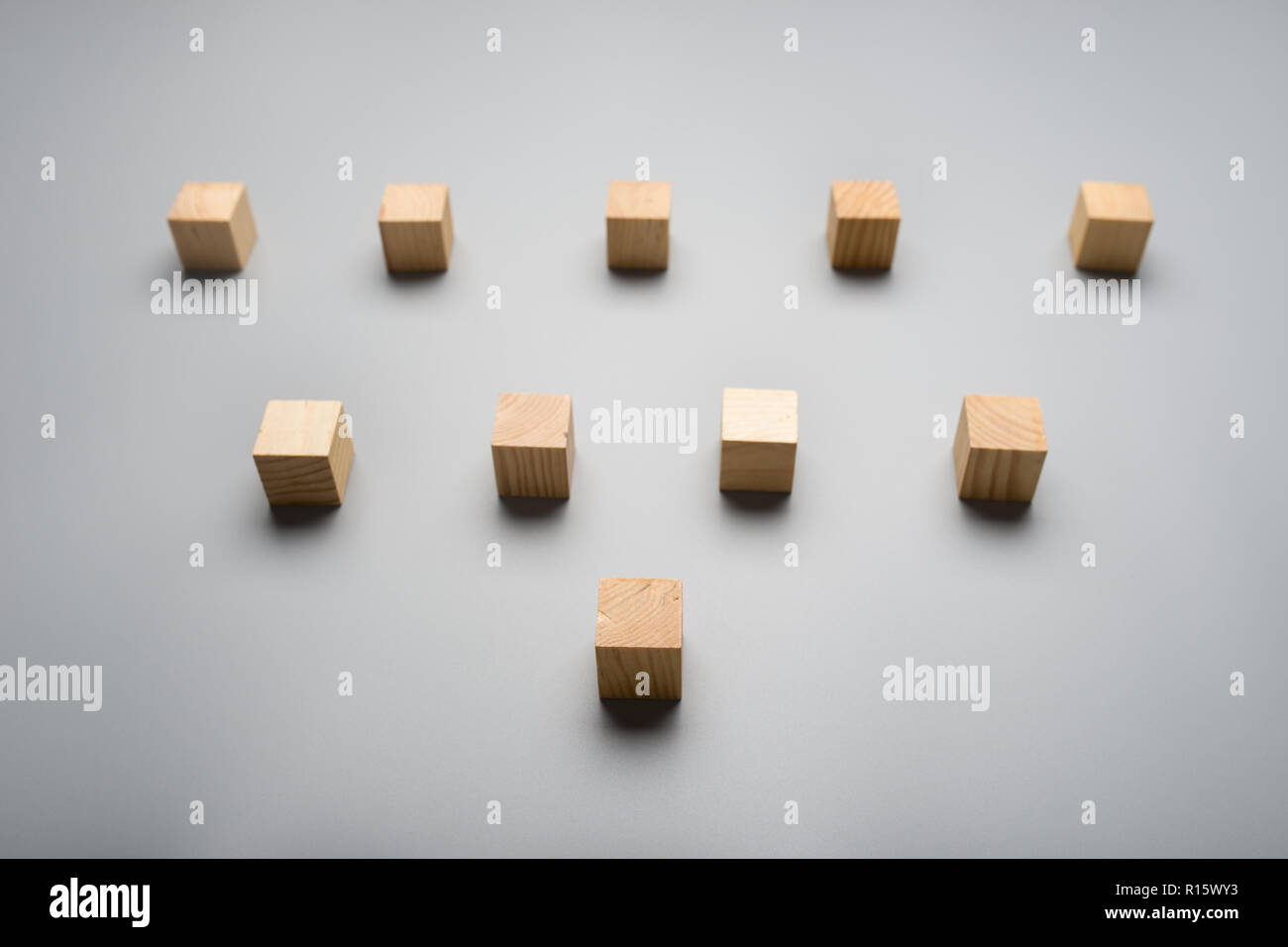 Ten blank wooden cubes placed over grey background in a triangle shape ...