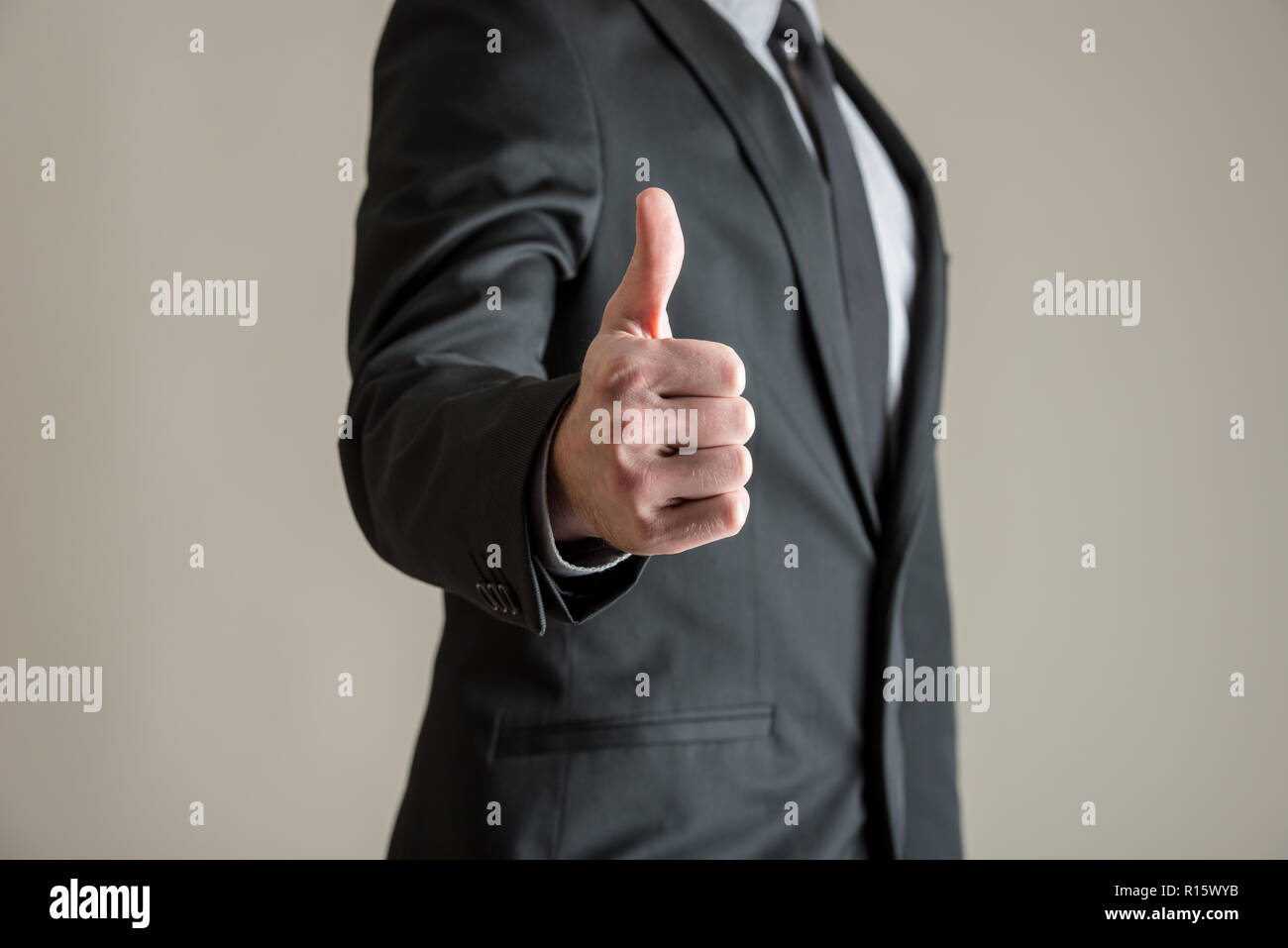 Front view of businessman showing a thumbs up sign over grey background ...