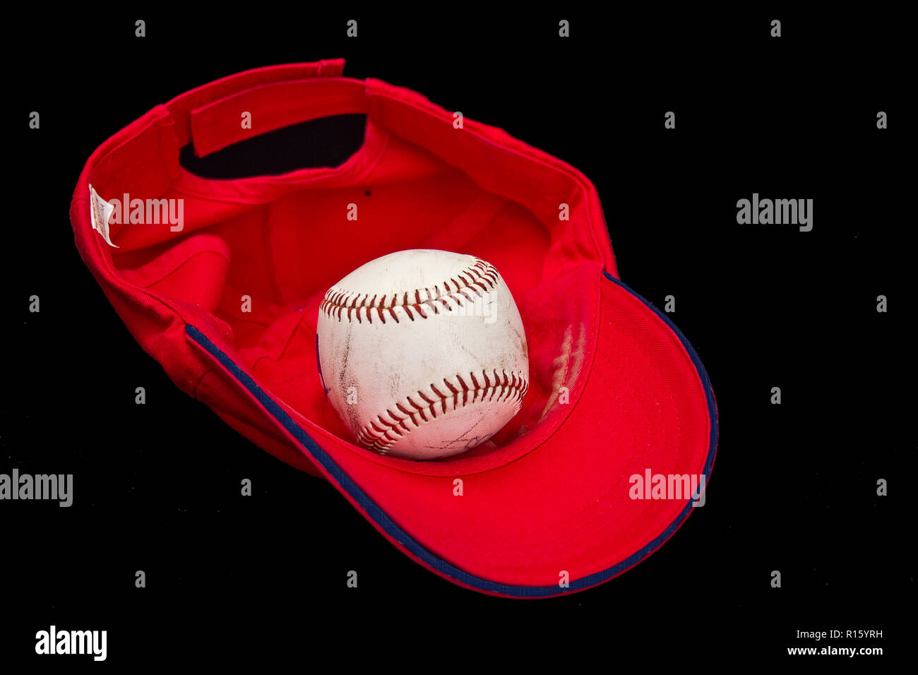Red baseball hat isolated on black background with worn baseball ...
