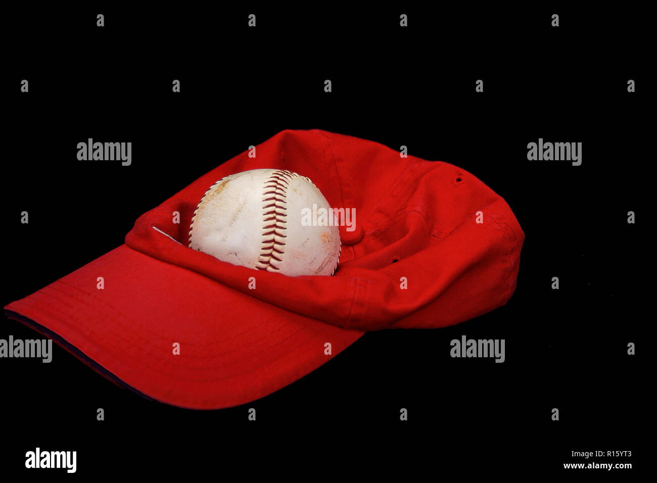 Red baseball hat isolated on black background with worn baseball ...