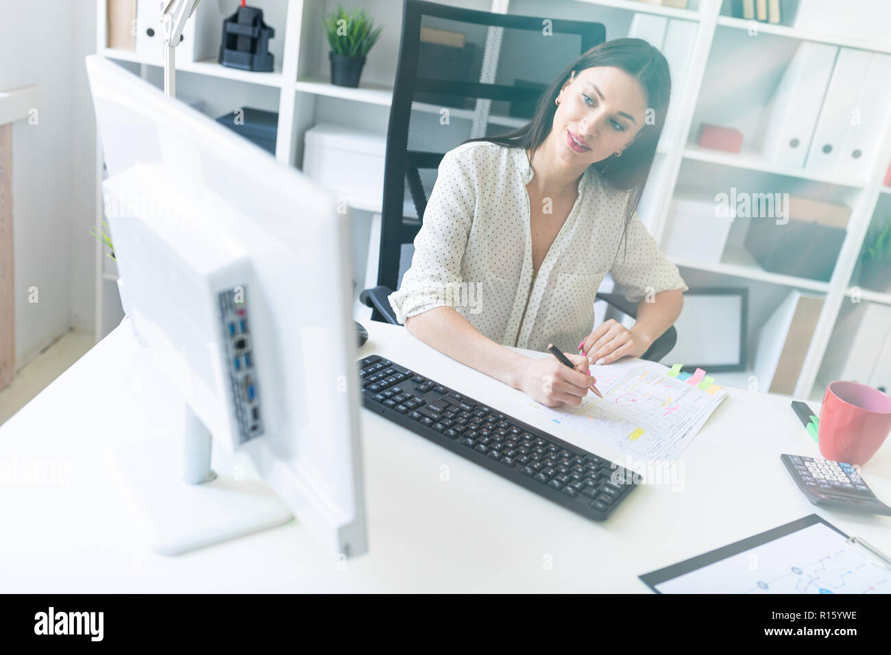 A young girl working in the office with documents and a computer ...