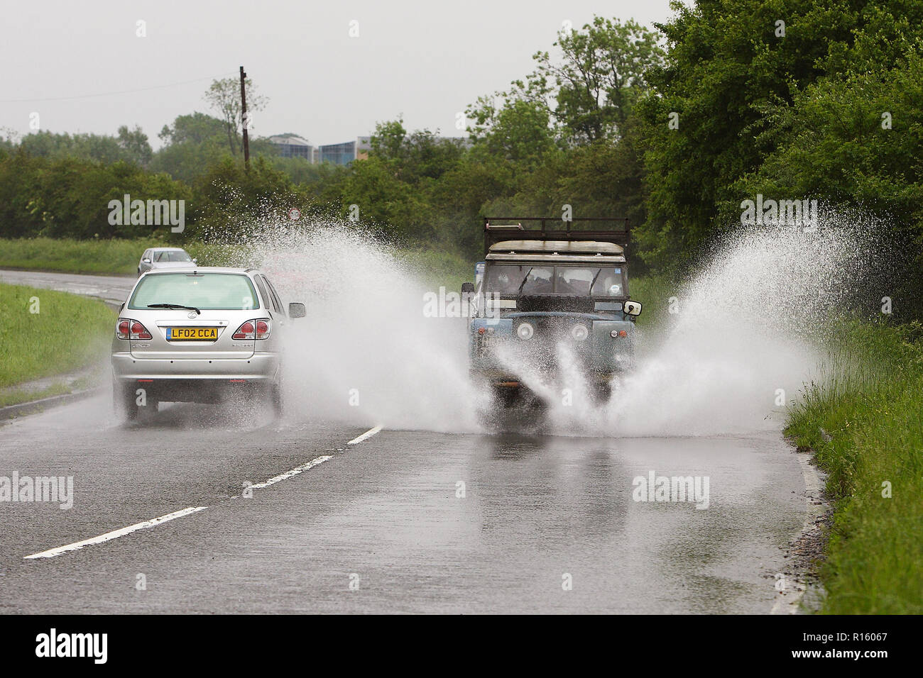 Cars and lorries being splashed by standing water on a road after ...