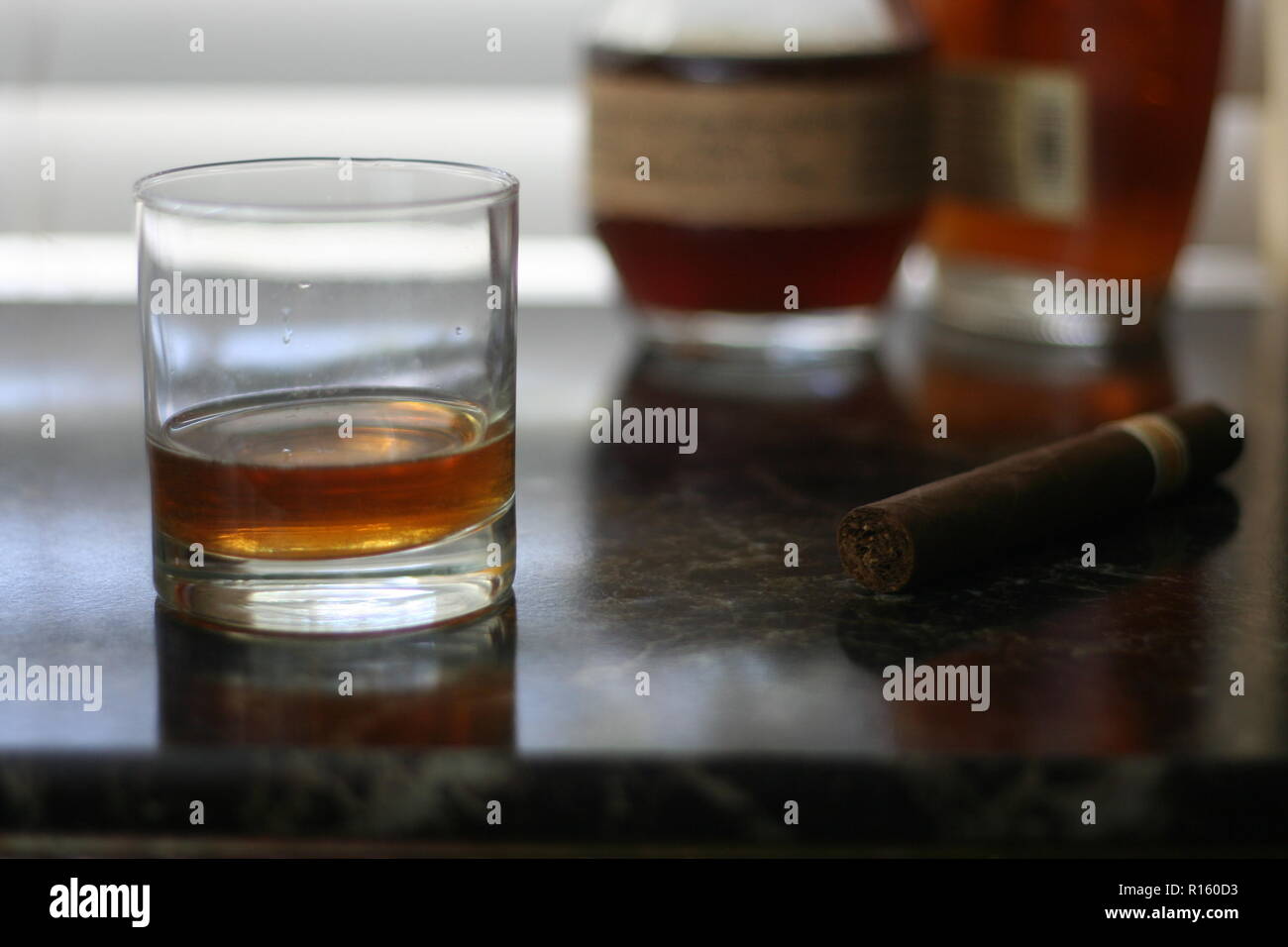 Whiskey glass, bottles and cigar on marble table Stock Photo - Alamy